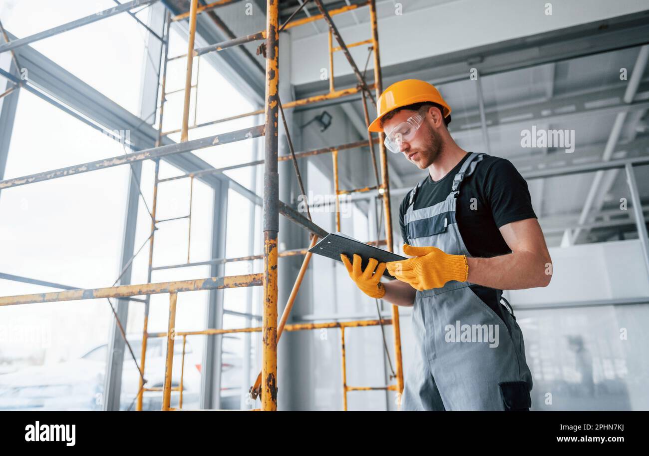 Engineer in grey uniform with notepad in hands works indoors in modern ...