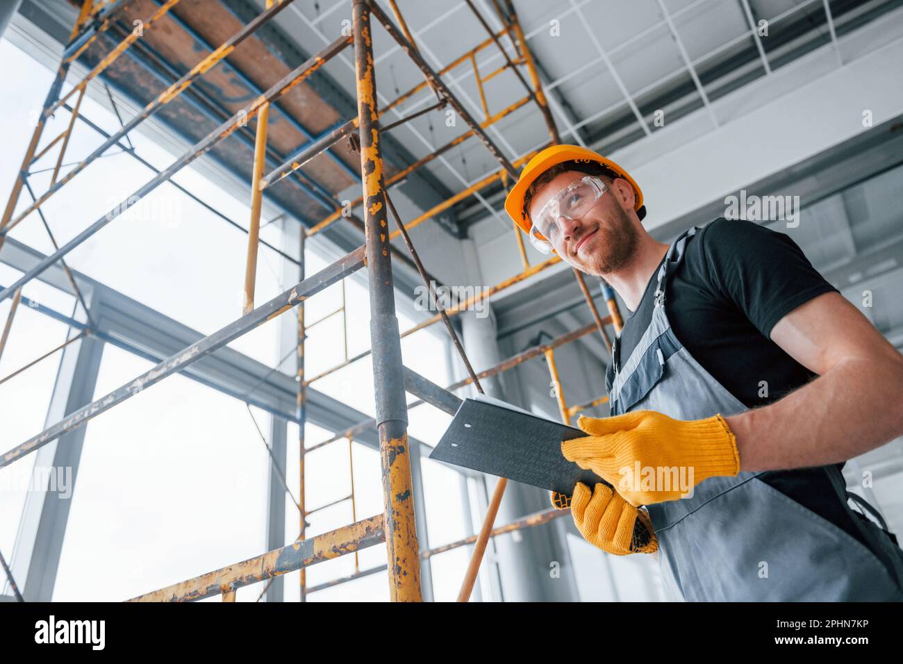 Engineer in grey uniform with notepad in hands works indoors in modern ...