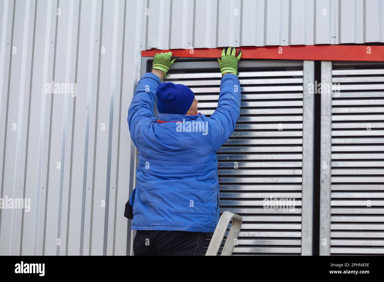 Worker installing window shutters with blinds on house or industrial ...