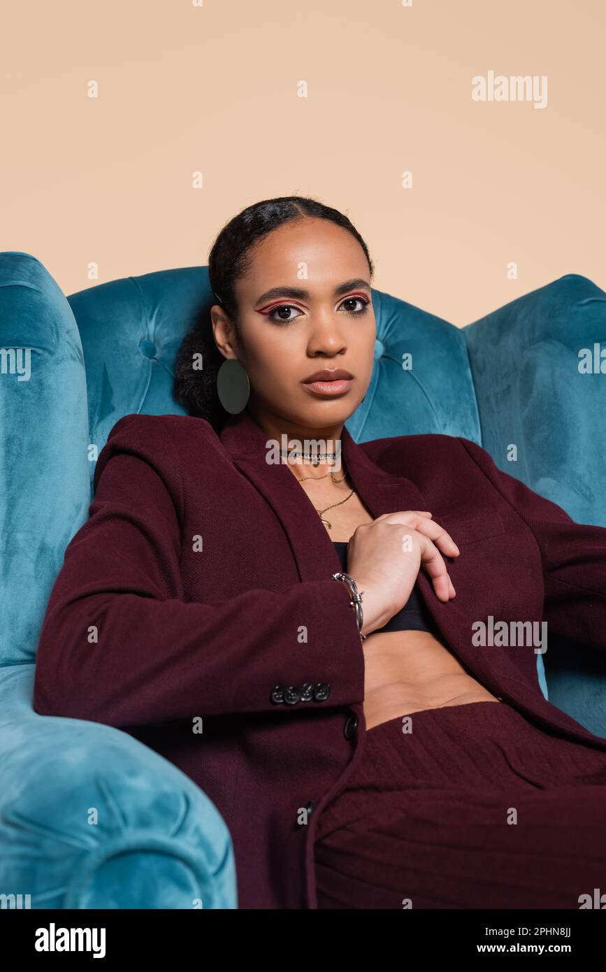 pretty african american model in maroon suit sitting on blue velvet ...