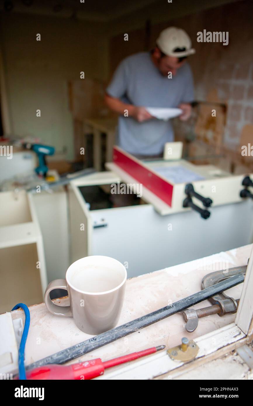 Kitchen Fitters: Manual Worker. Focus on a foreground mug with a ...
