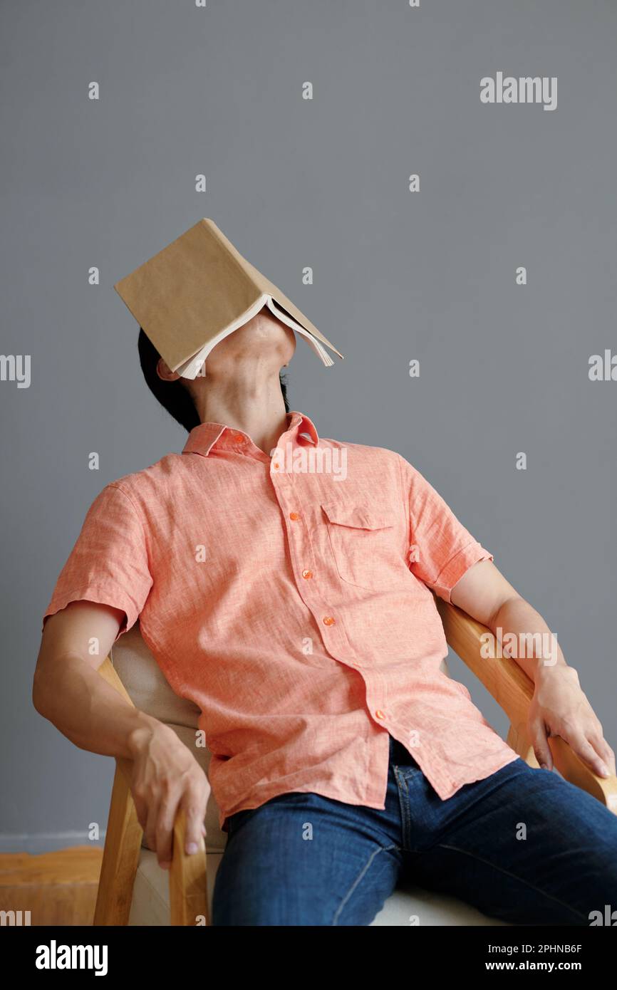Young man fell asleep on chair with opened book on his face Stock Photo ...
