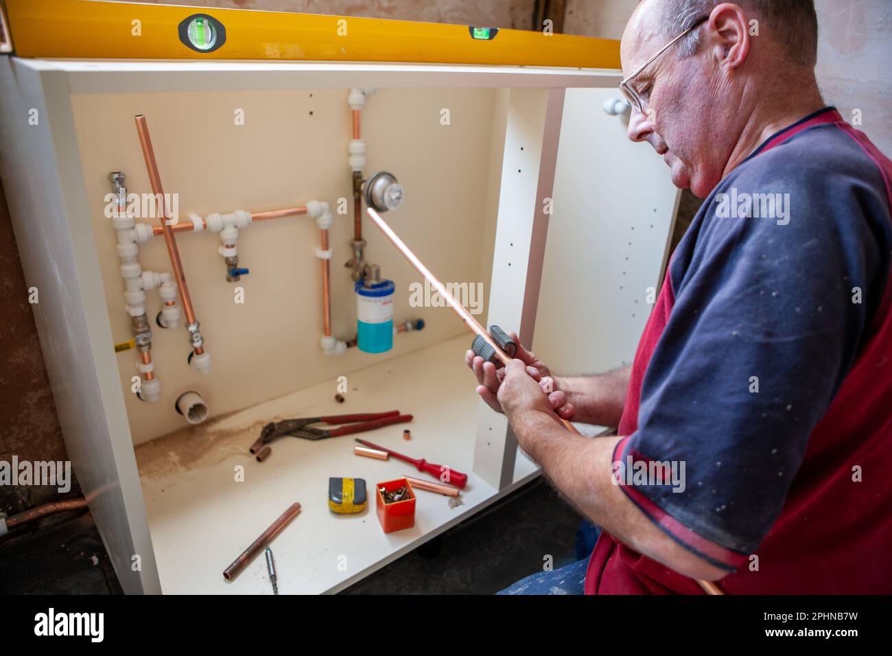 Kitchen Fitters: Plumbing the Sink. A plumber trimming copper pipe to ...