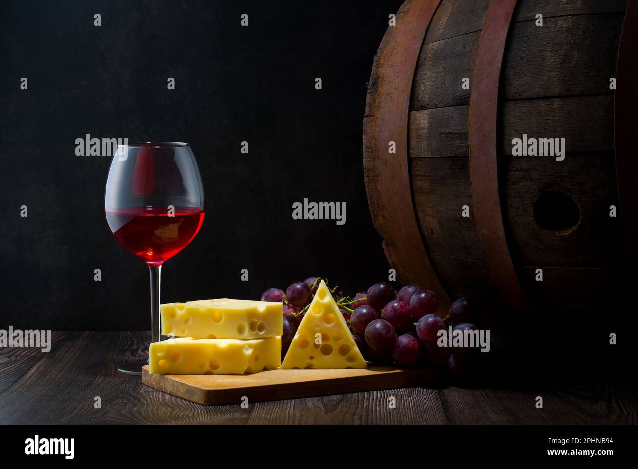 Red wine in low light with cheese and grape,wine barrel and glass,still ...