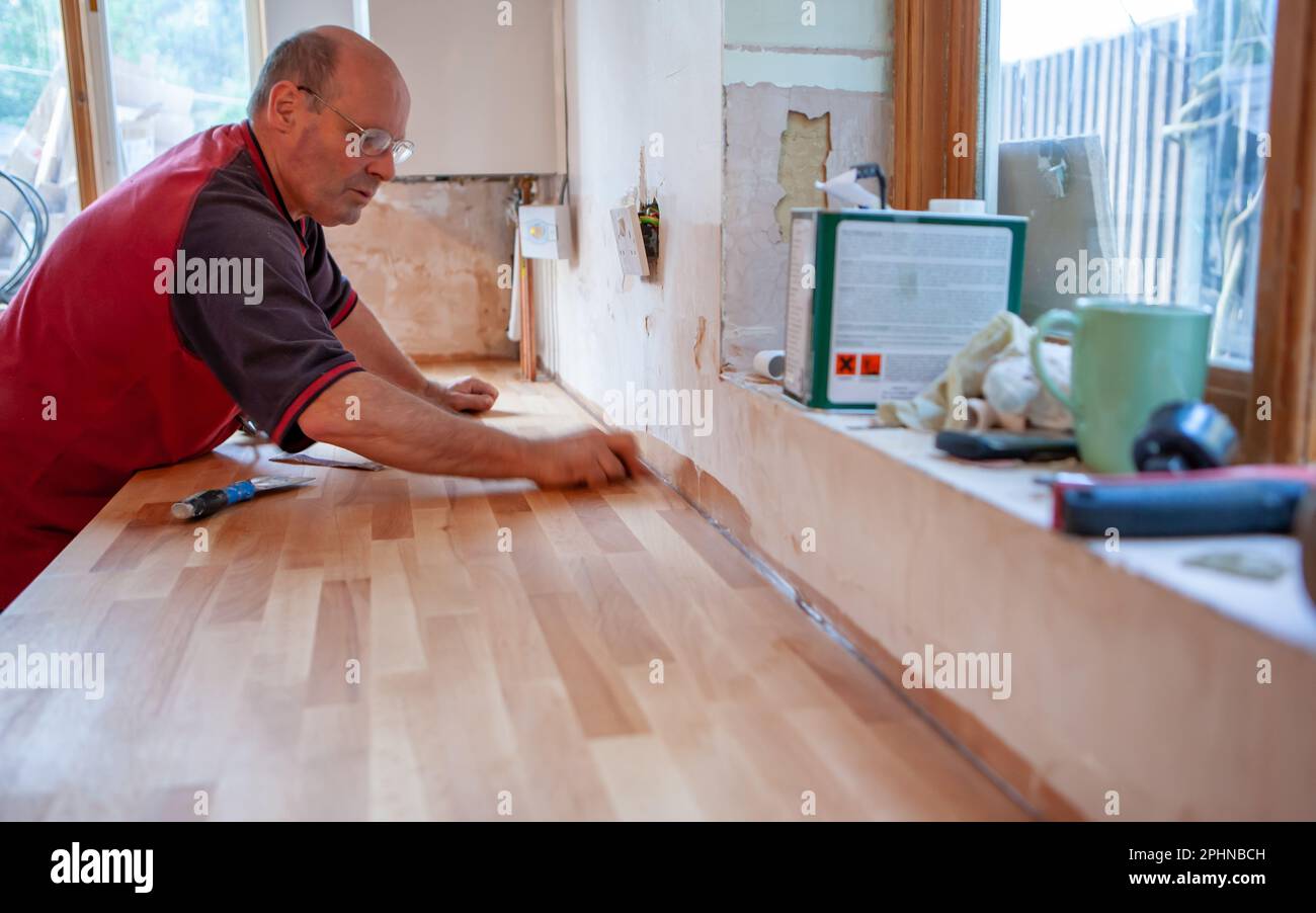 Kitchen Fitters: Wooden Worktop. A fitter applying silicon sealant to ...