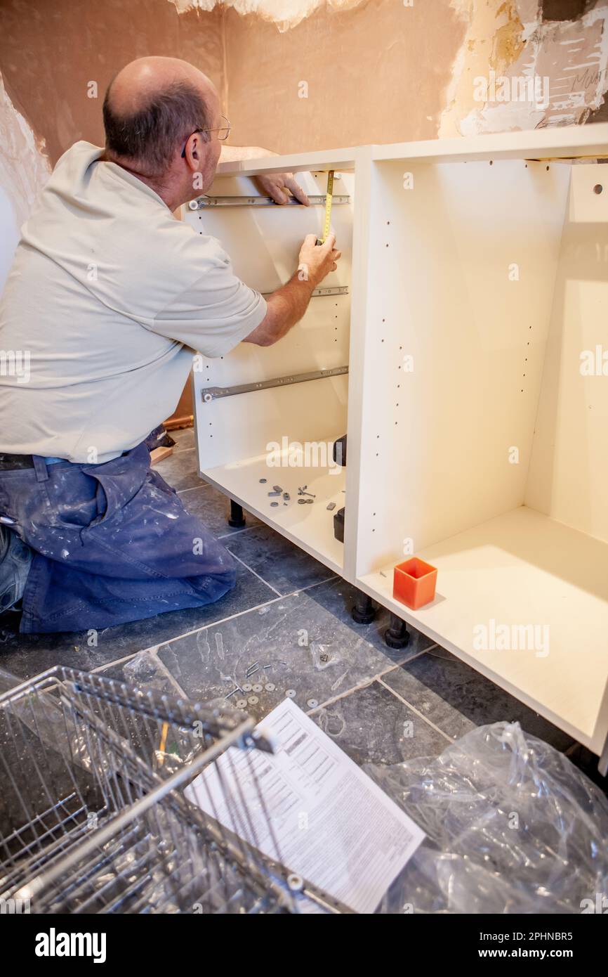 Kitchen Fitters: Fitting the Drawers. A fitter measuring drawer runners ...