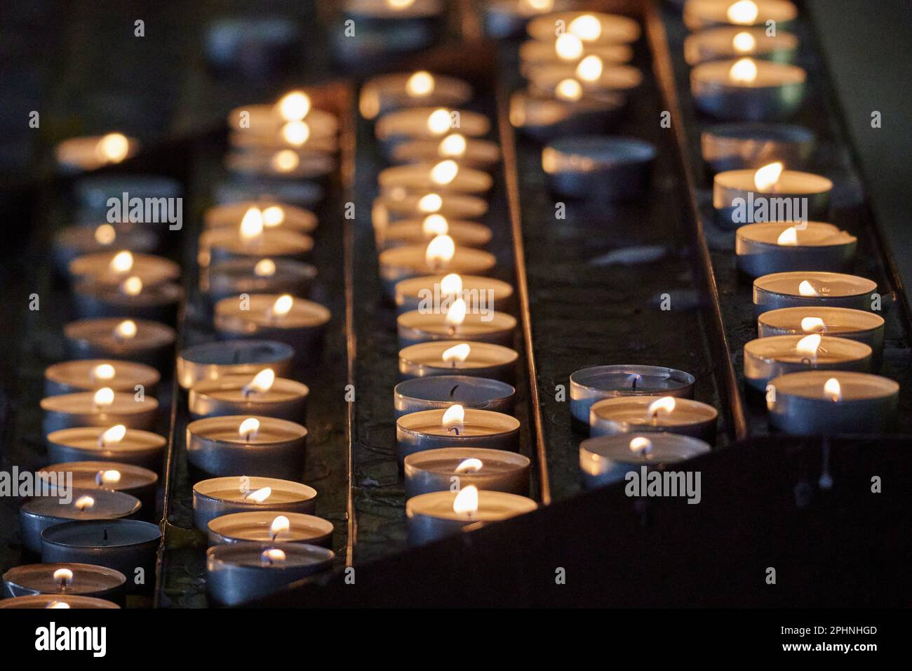 A close-up shot of multiple lit votive candles in a church setting ...