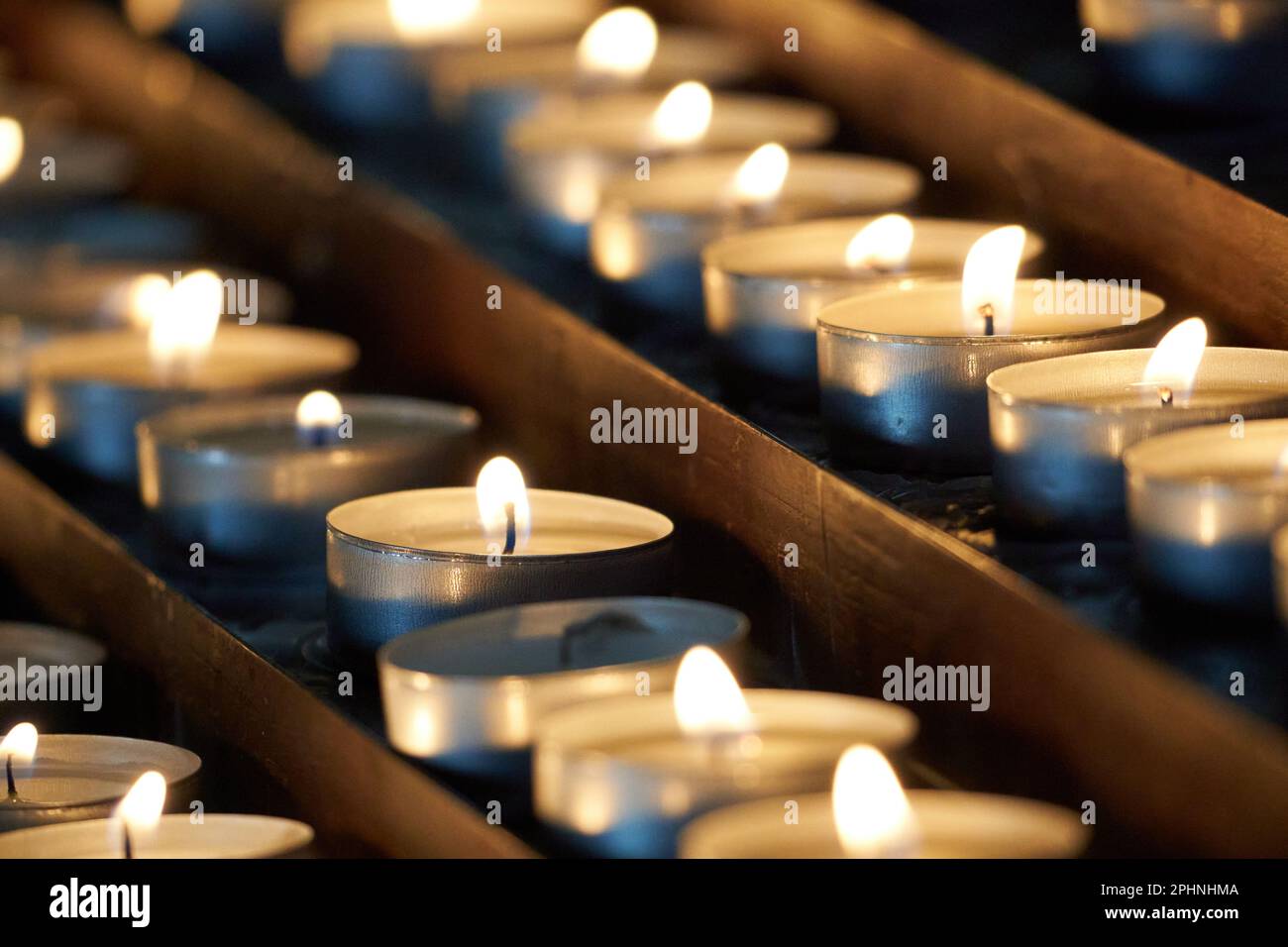 A close-up shot of multiple lit votive candles in a church setting ...