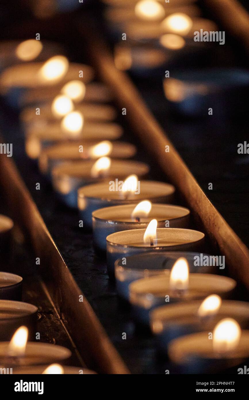 A close-up shot of multiple lit votive candles in a church setting ...