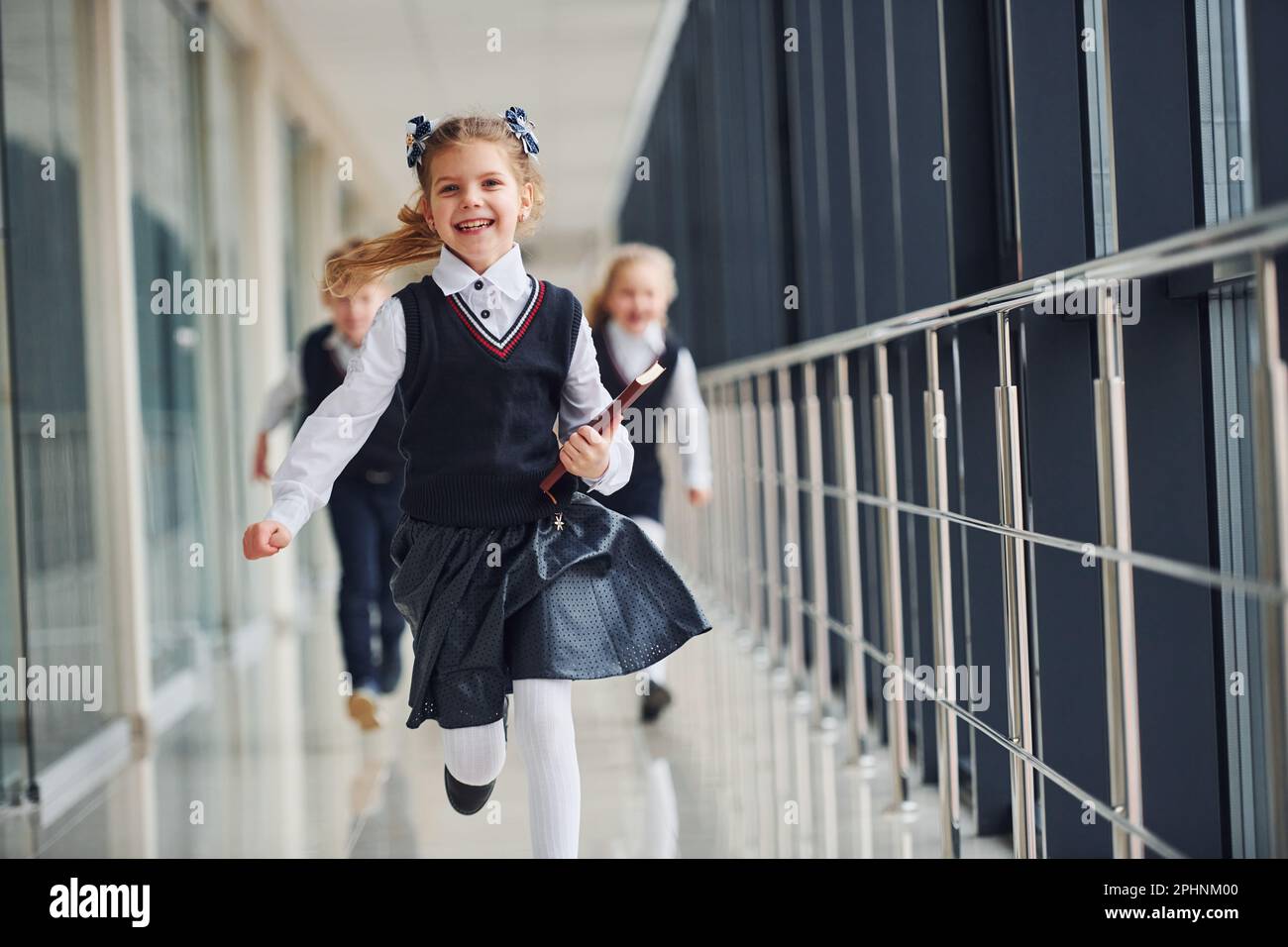 Active school kids in uniform running together in corridor. Conception ...
