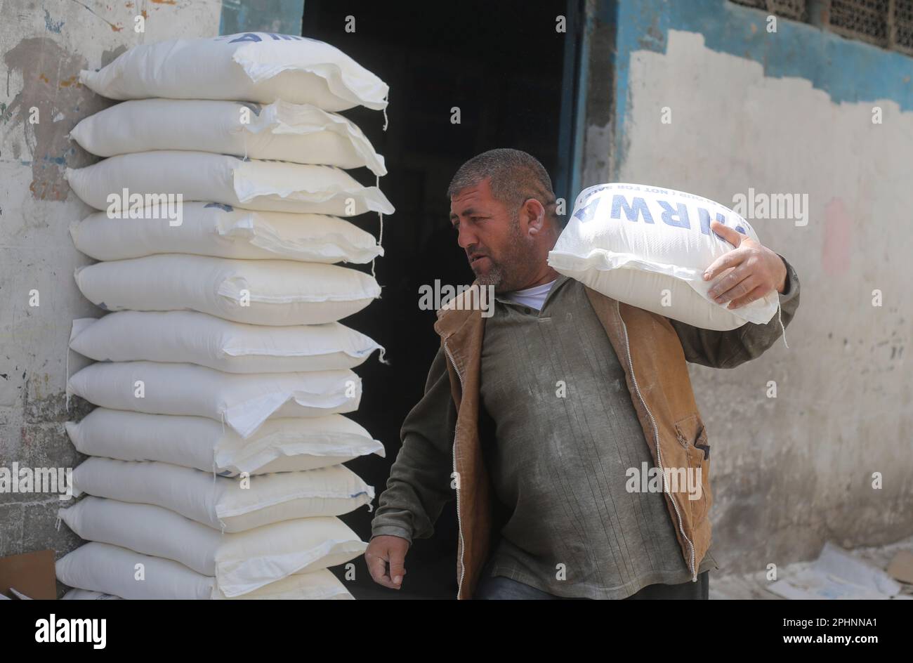Gaza. 29th Mar, 2023. A Palestinian worker carries a sack of flour ...