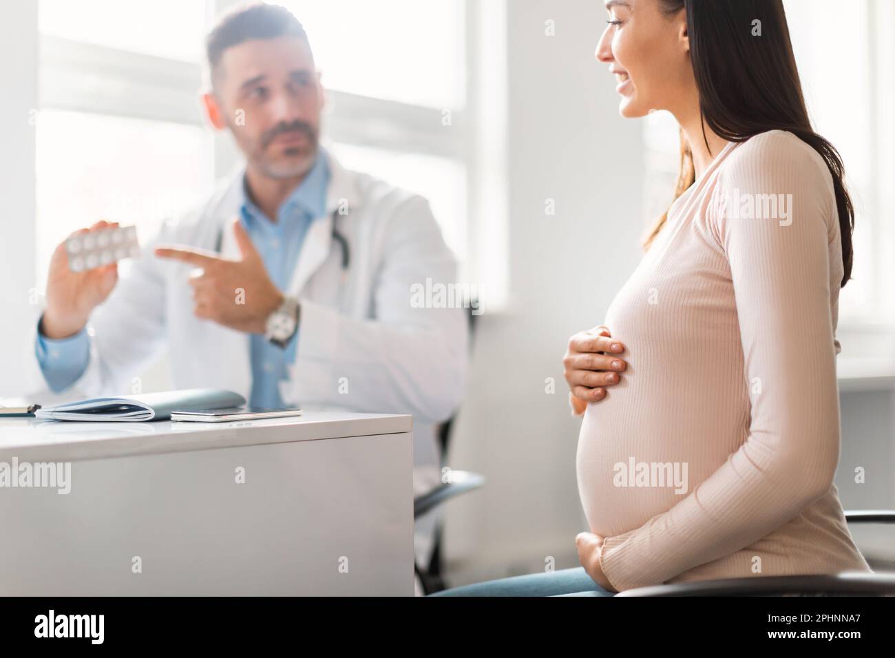 Pregnancy and medicine concept. Male gynecologist giving pills to ...
