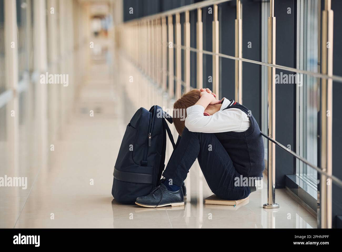 Boy in uniform sitting alone with feeling sad at school. Conception of ...