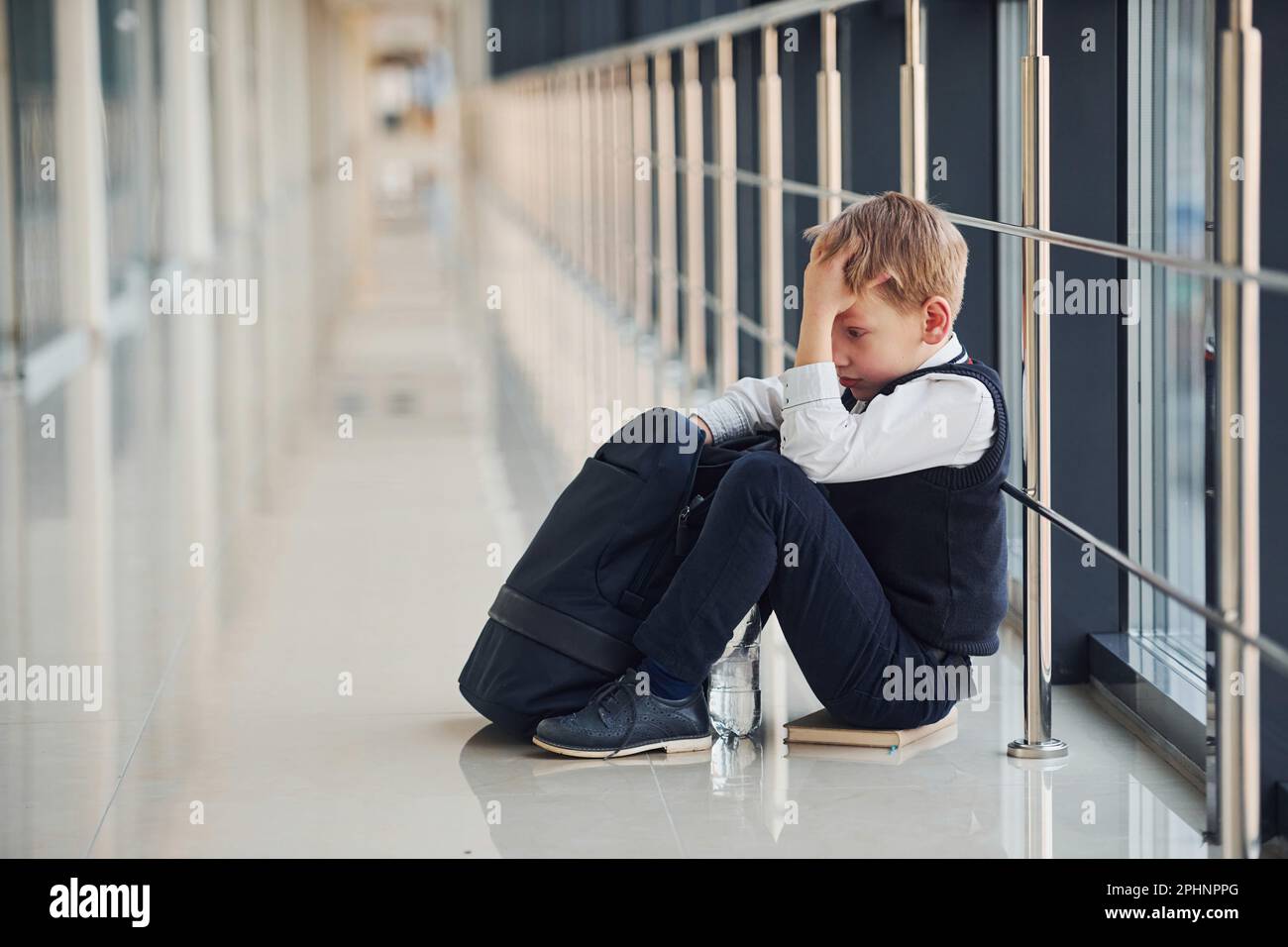 Boy in uniform sitting alone with feeling sad at school. Conception of ...
