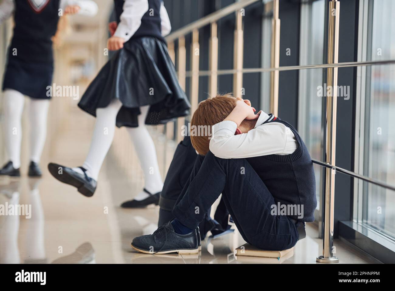 Boy in uniform sitting alone with feeling sad at school. Conception of ...
