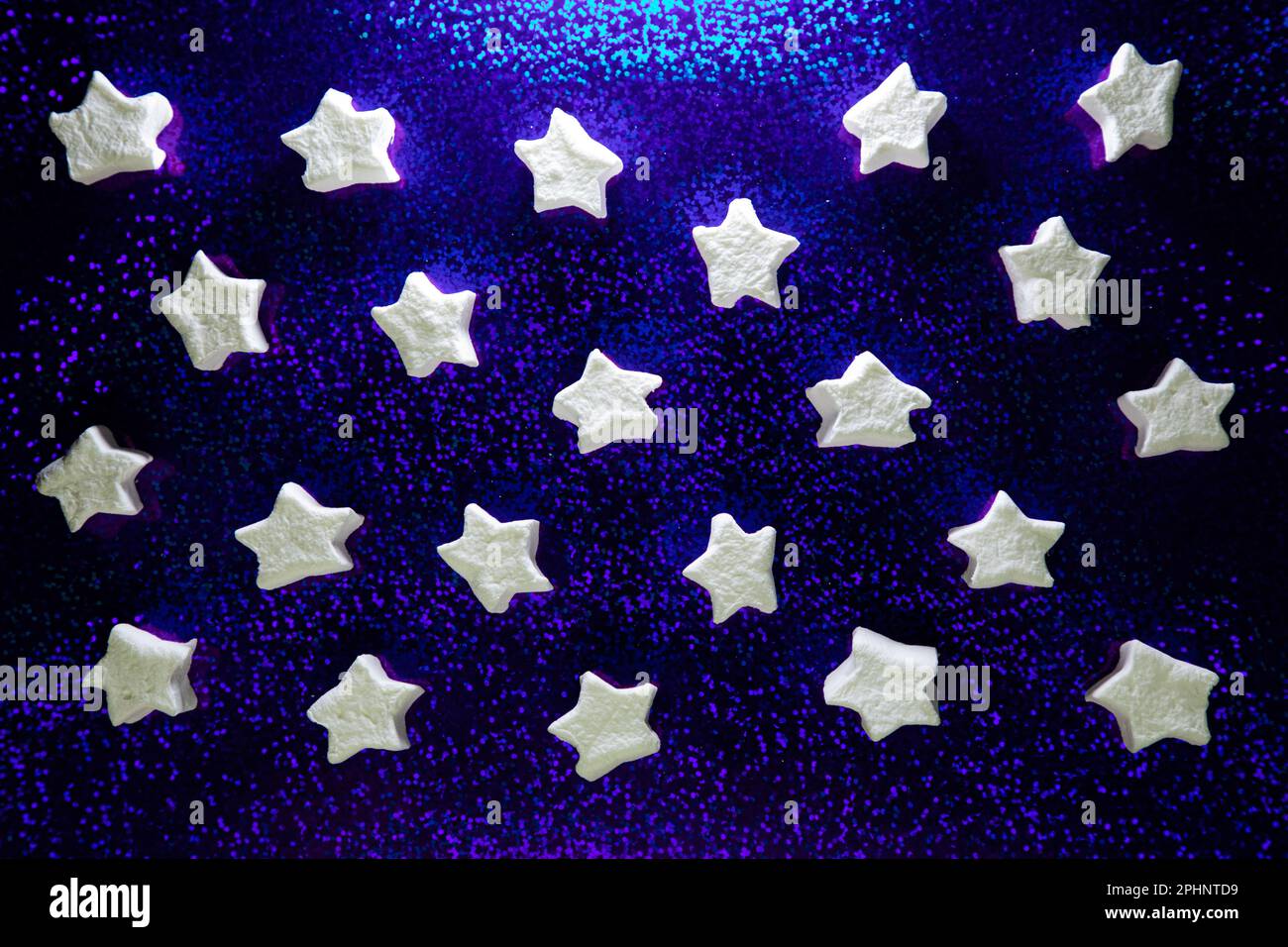 Marshmallow in the form of stars on the blue holographic background ...