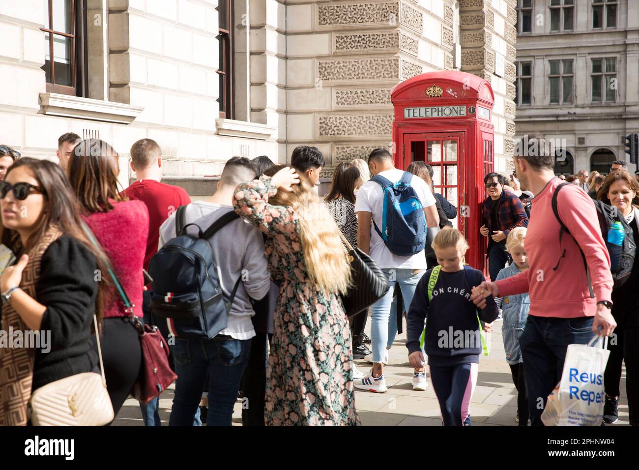 People queue to take photographs next to a red telephone box in ...