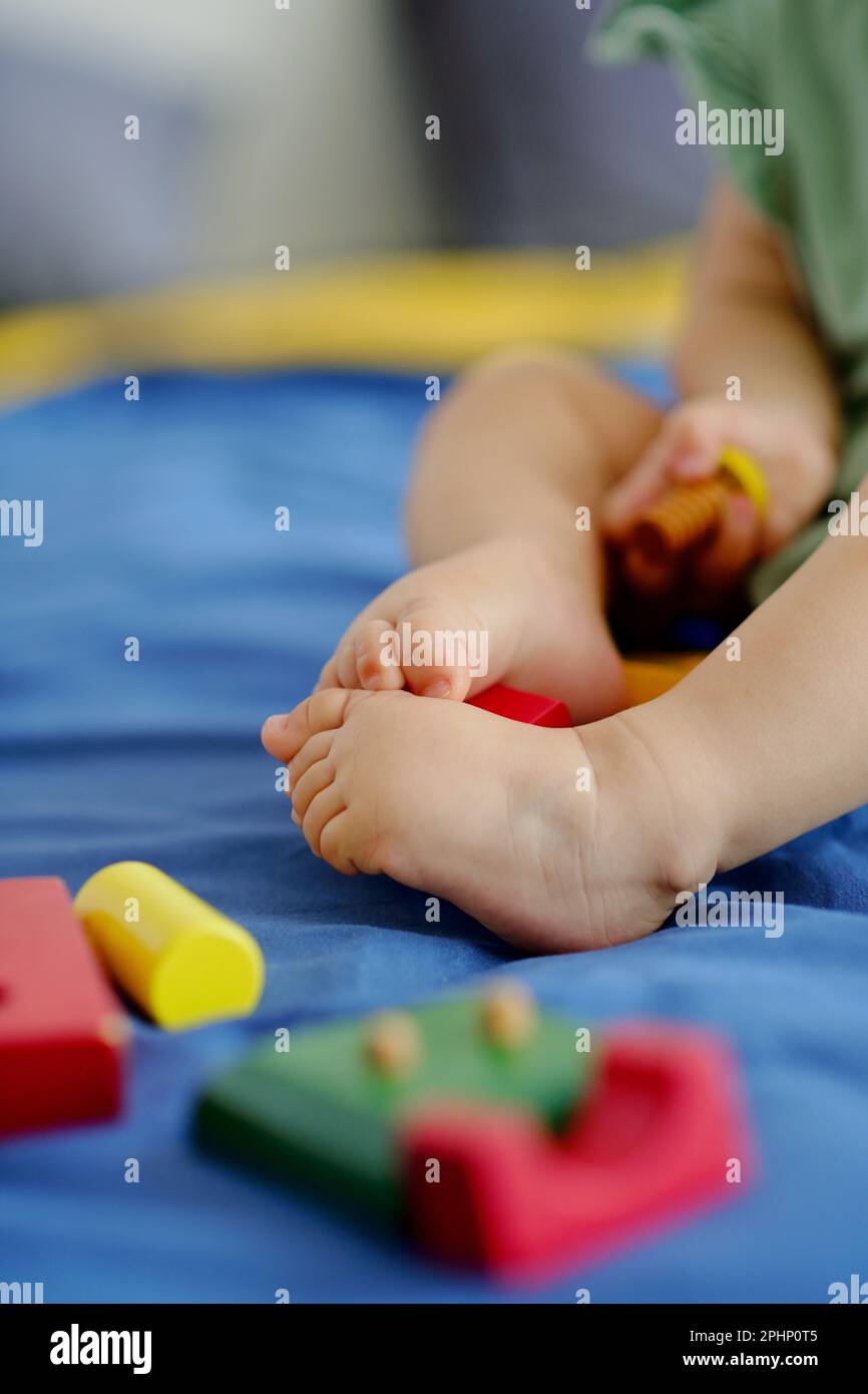 Feet of little baby playing with wooden toys on bed Stock Photo - Alamy
