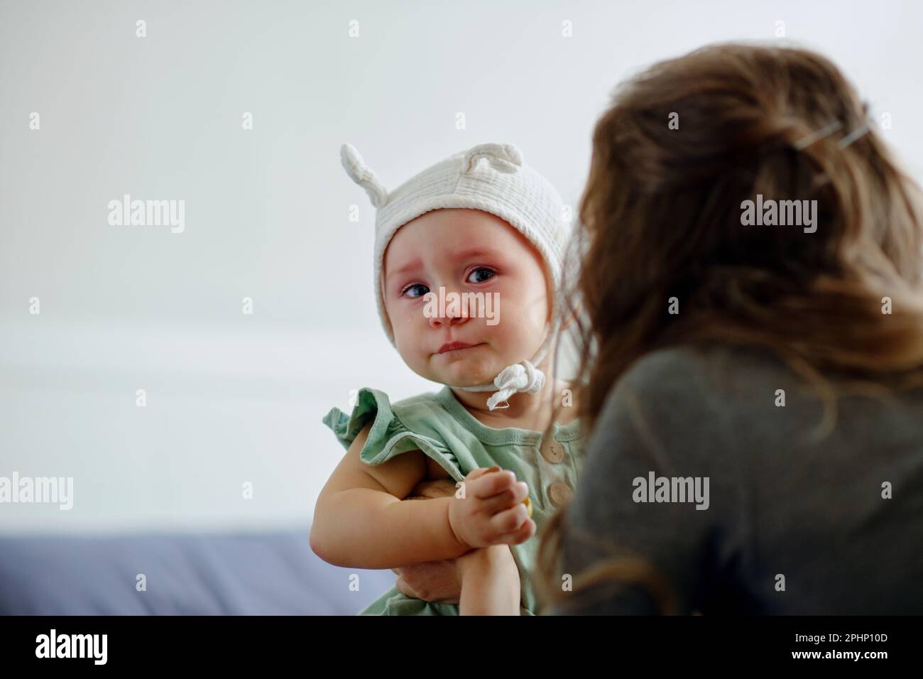 Crying toddler baby girl looking at camera when mother soothing her ...