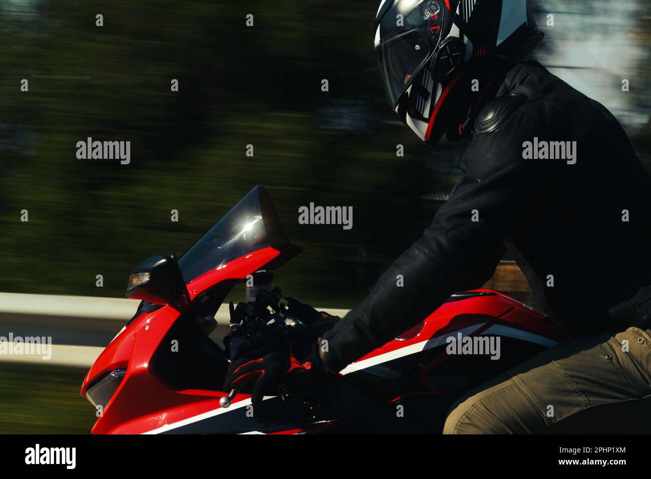 Side view of a motorcycle rider riding red race motorcycle on the ...