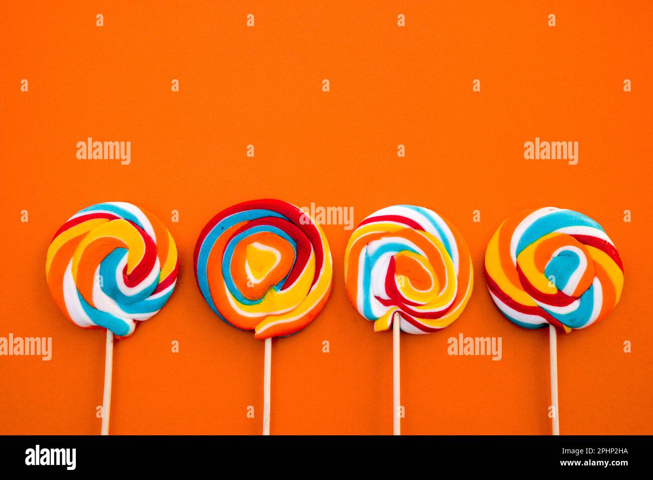 Colorful spiral lollipop candy on stick. On a orange background Stock ...