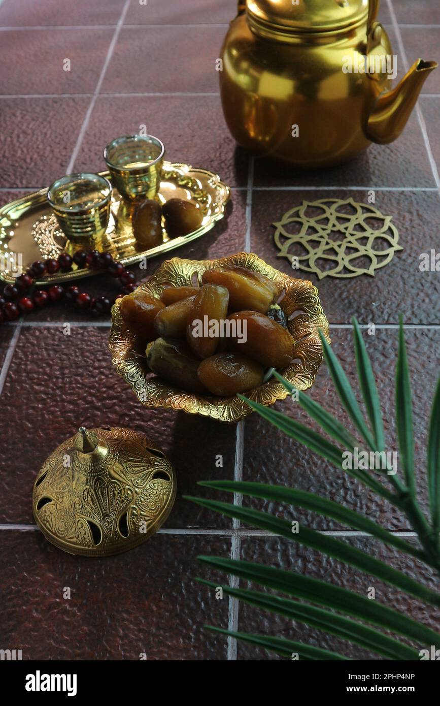 dates in a gold bowl against a background of glasses on a gold tray and ...