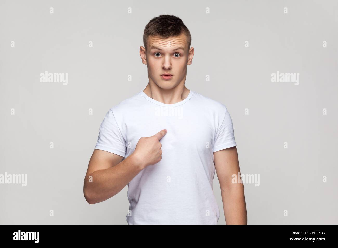 Portrait of surprised shocked teenager boy wearing T-shirt standing ...