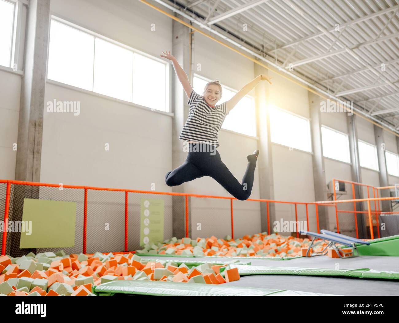 Pretty girl in trampoline park jumping with split and smiling. Happy ...