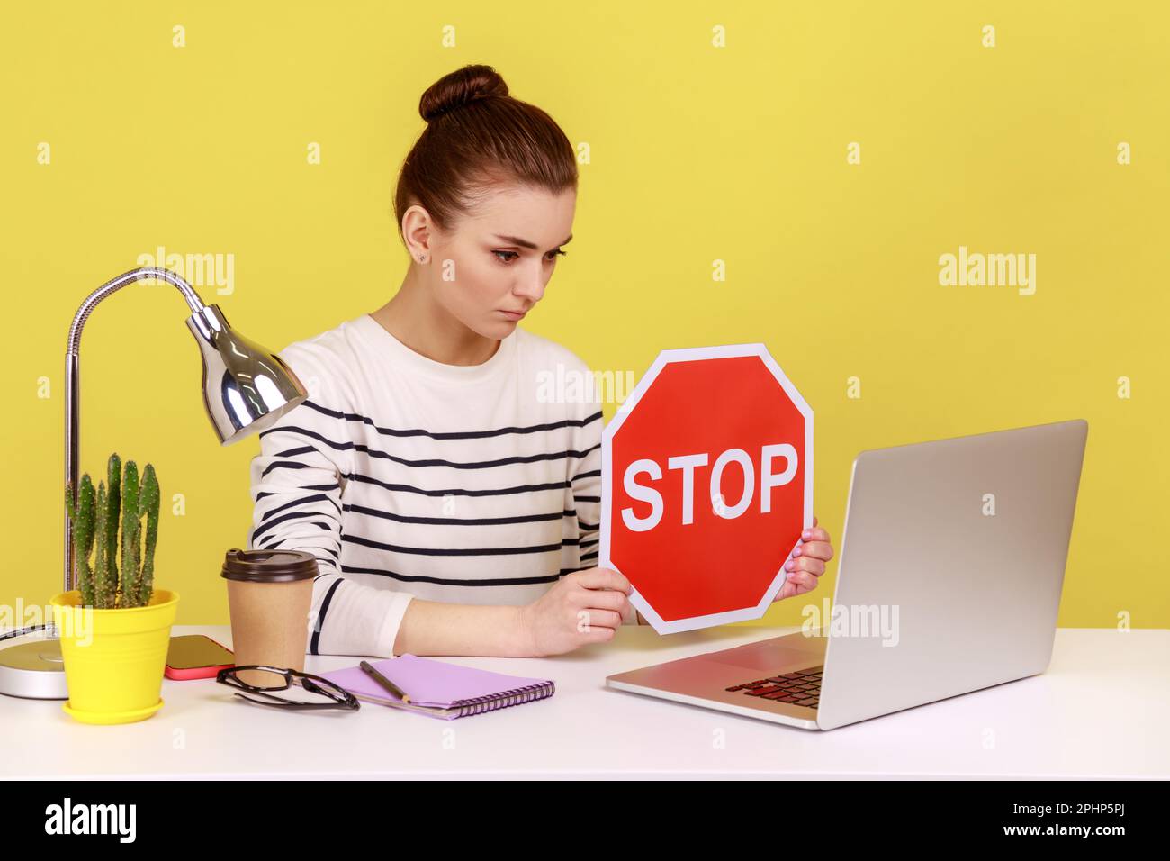 Woman manager wearing striped shirt showing stop red sign to laptop ...