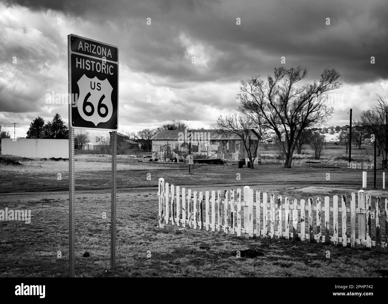 A white picket fence stands next to a sign for historic Route 66 stands ...