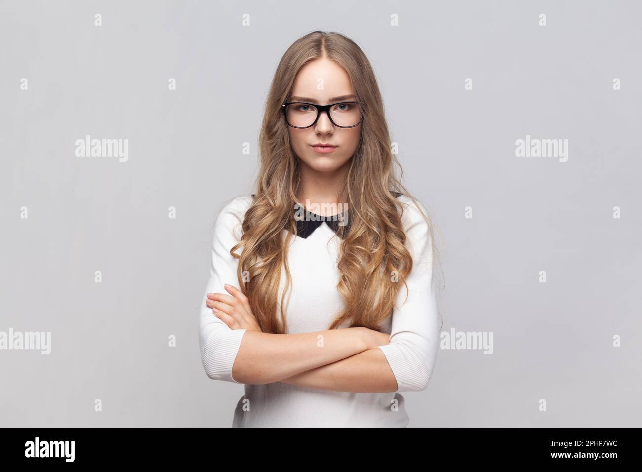 Portrait of serious strict young adult woman in glasses with wavy blond ...