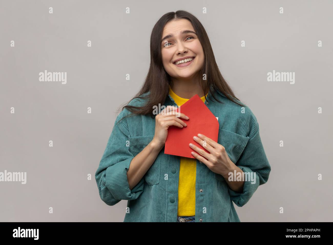 Portrait of pleased young woman holding envelope and reading letter ...