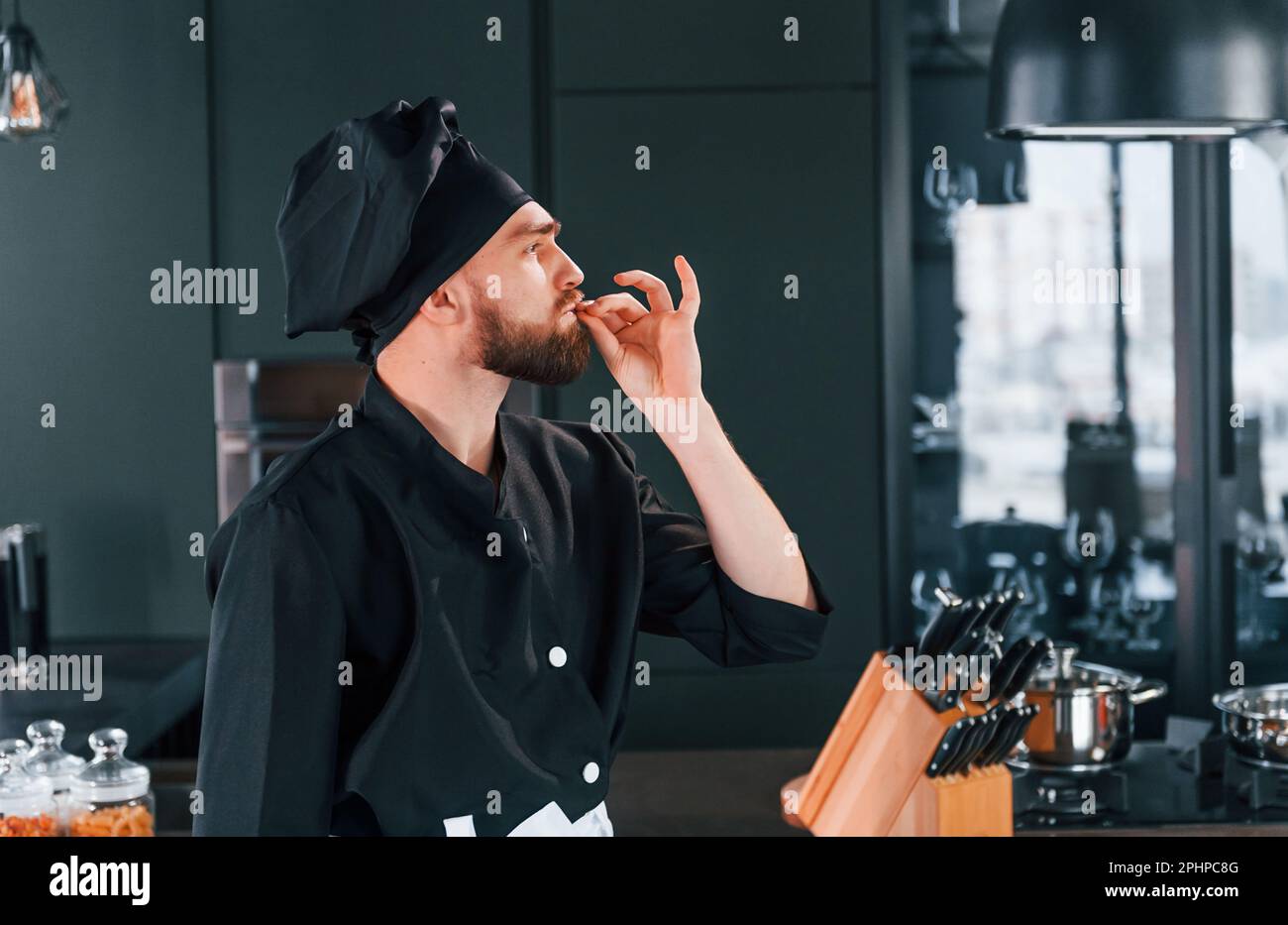 Side view of professional young chef cook in uniform that standing on ...