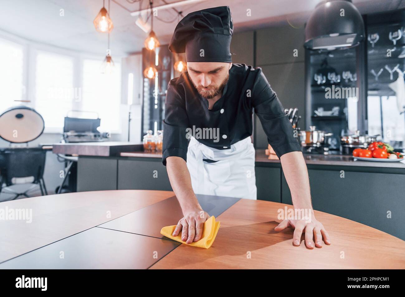 Professional young chef cook in uniform cleaning table on the kitchen ...