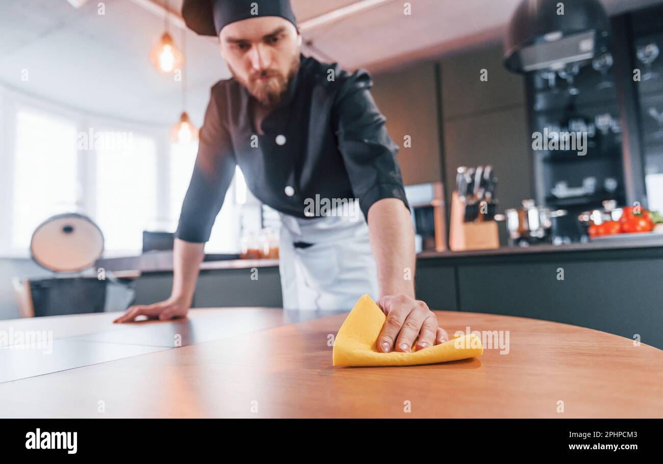 Professional young chef cook in uniform cleaning table on the kitchen ...