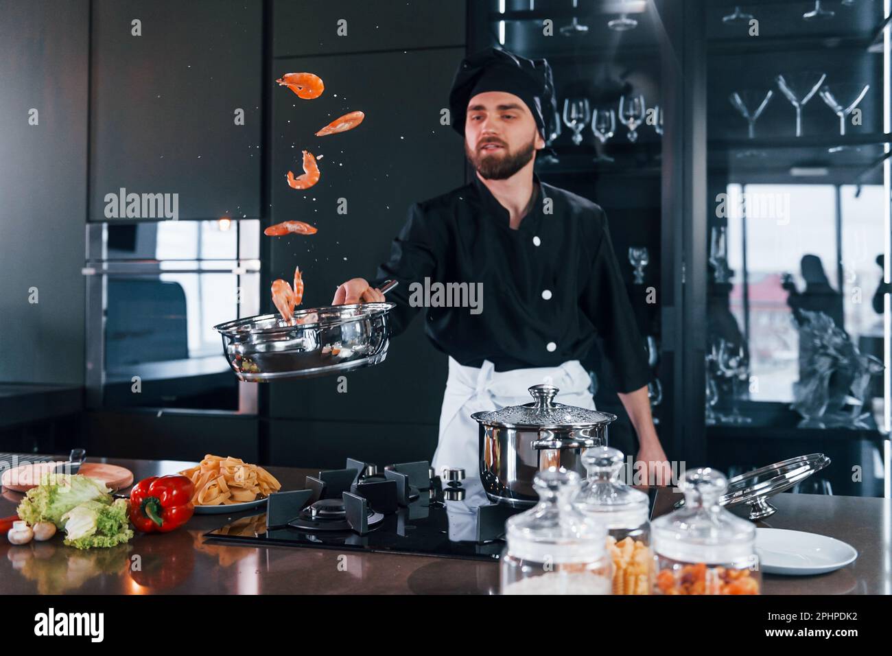 Professional young chef cook in uniform frying food on the kitchen ...