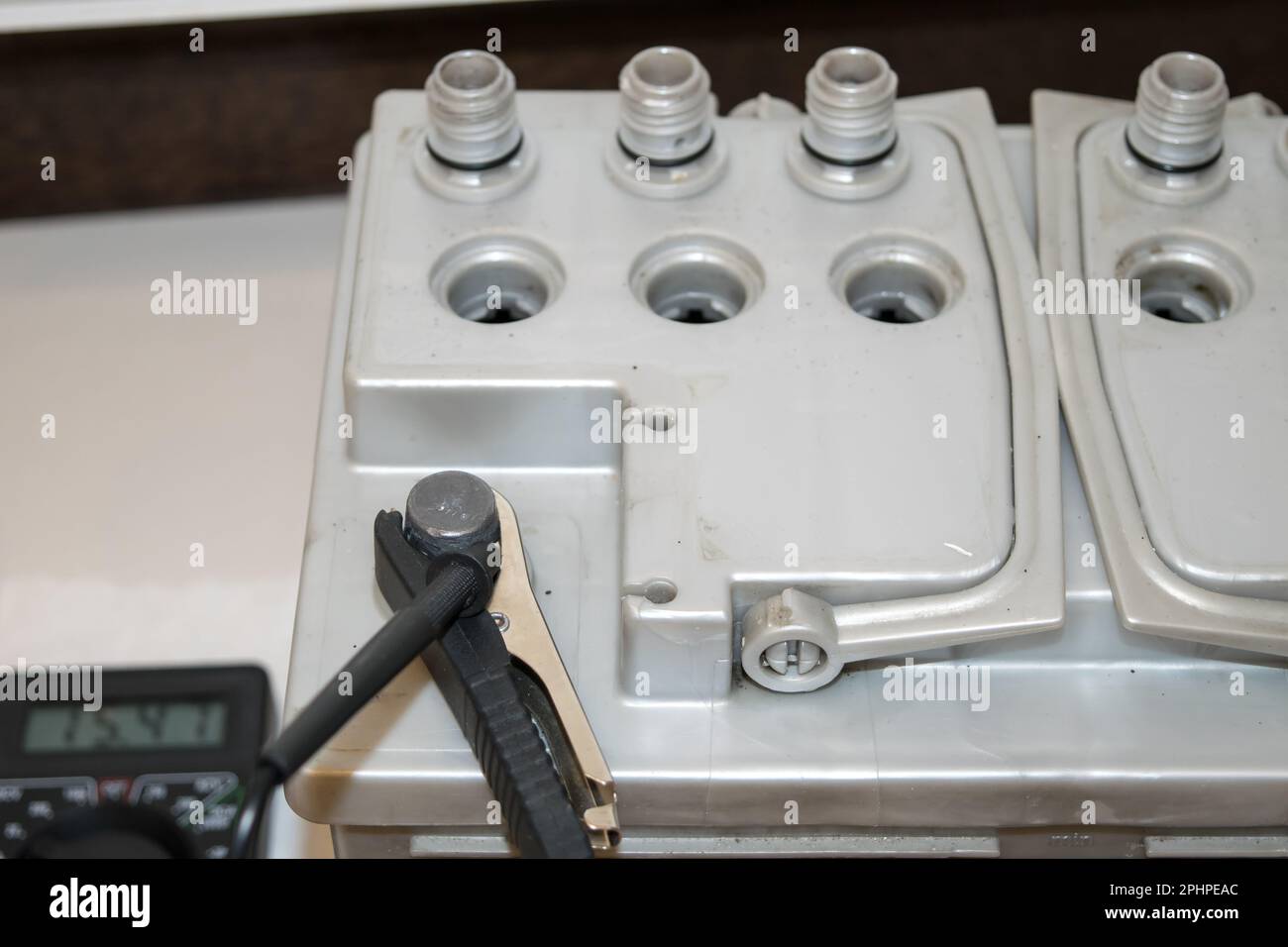 Car battery charging. Gray battery with caps unscrewed, charger cables ...