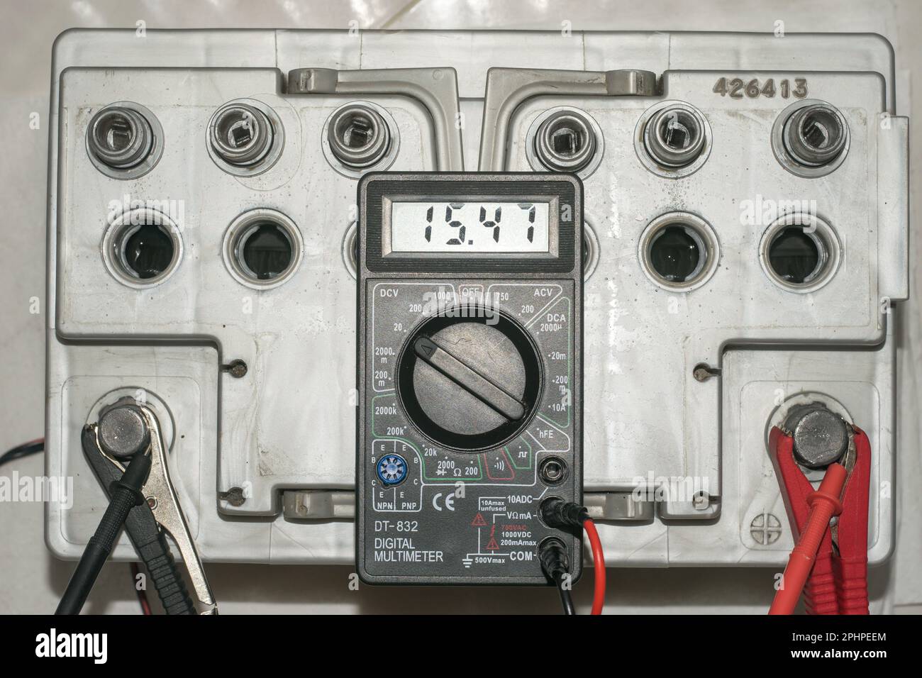 Car battery charging. Gray battery with caps unscrewed, charger cables ...