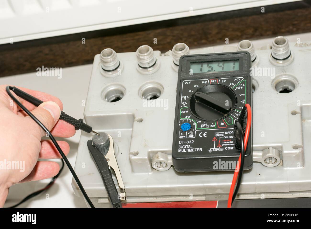 Car battery charging. Gray battery with caps unscrewed, charger cables ...