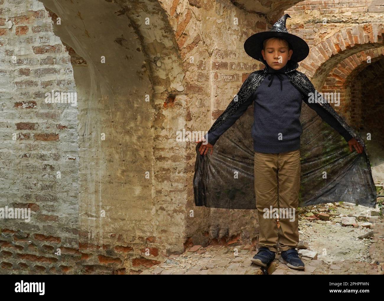 A boy wizard with his eyes closed and his hands spread stands in the ...