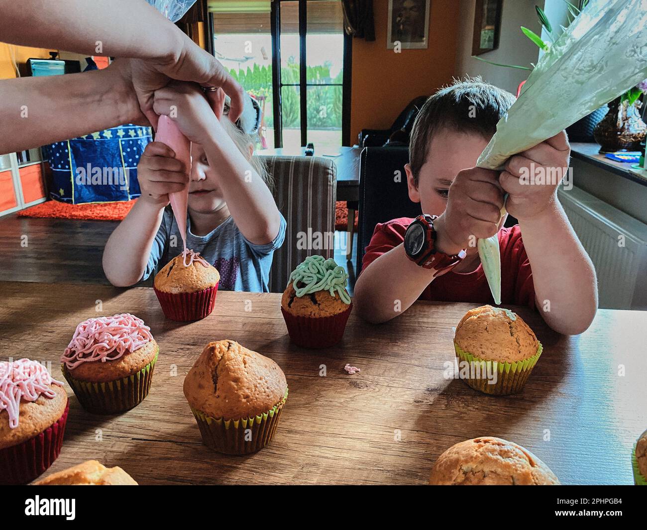 Group of children baking cupcakes, squeezing cream from confectionery ...