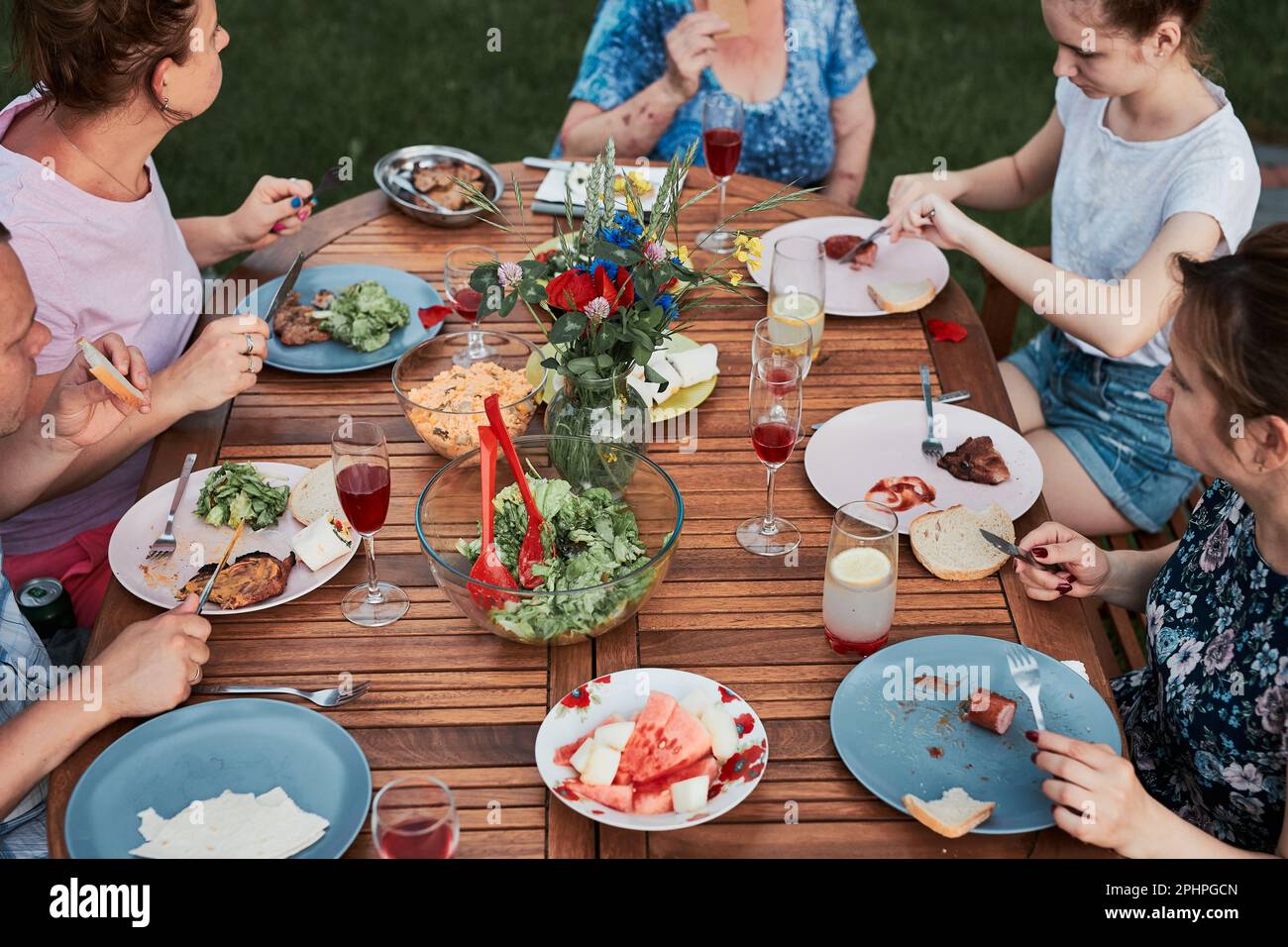 Family having a meal from grill during summer picnic outdoor dinner in ...