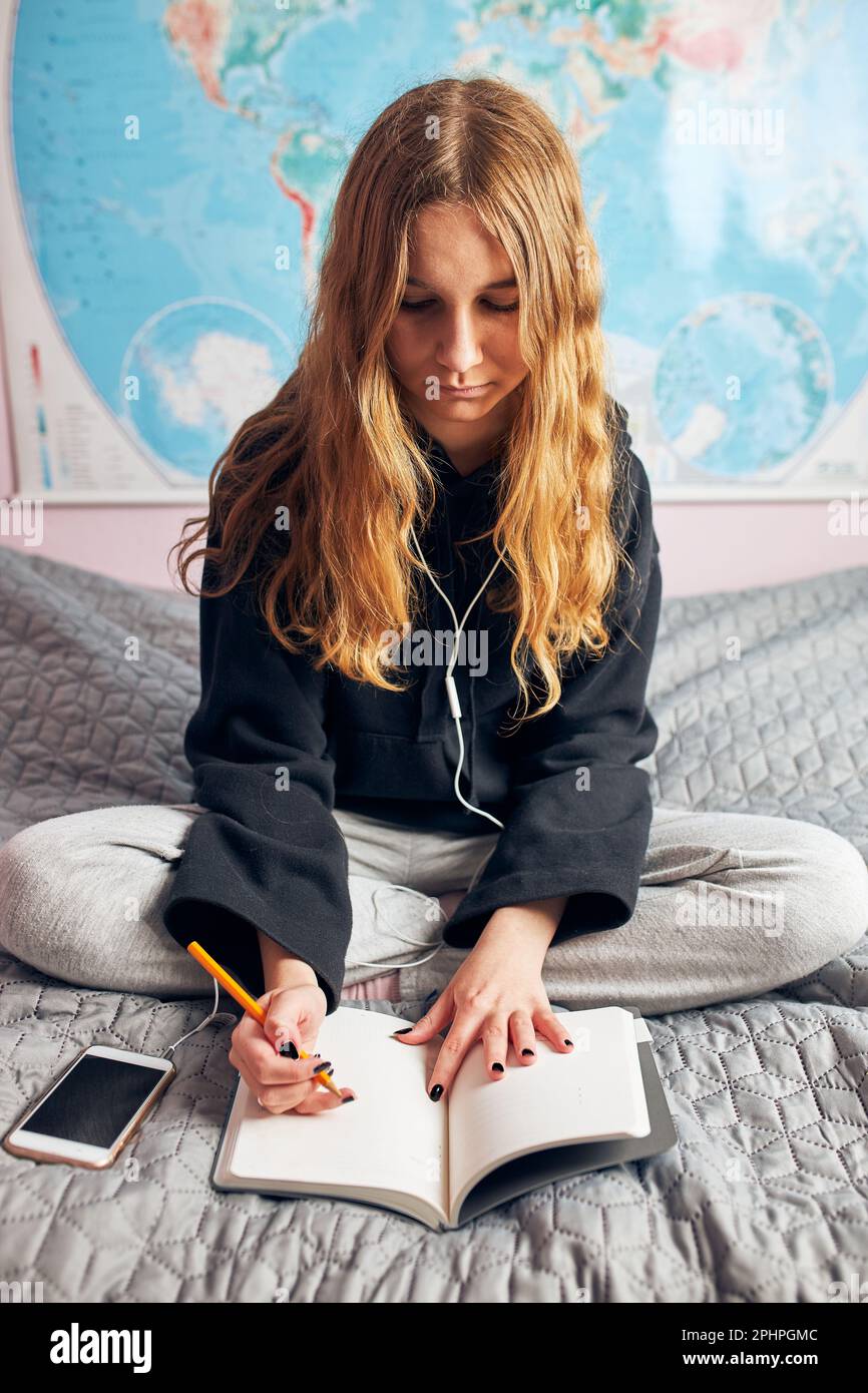 Student learning at home. Young woman making notes, reading and ...