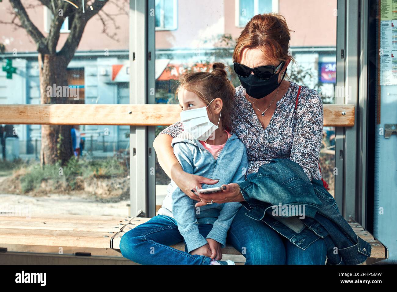 Woman and her child waiting for a bus sitting at bus stop of public ...