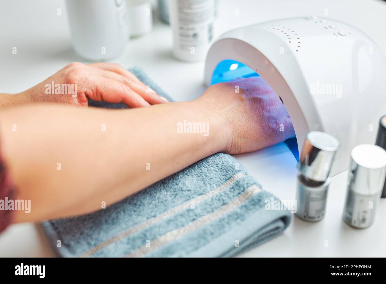 Woman applying gel hybrid polish using UV lamp. Beauty wellness spa ...