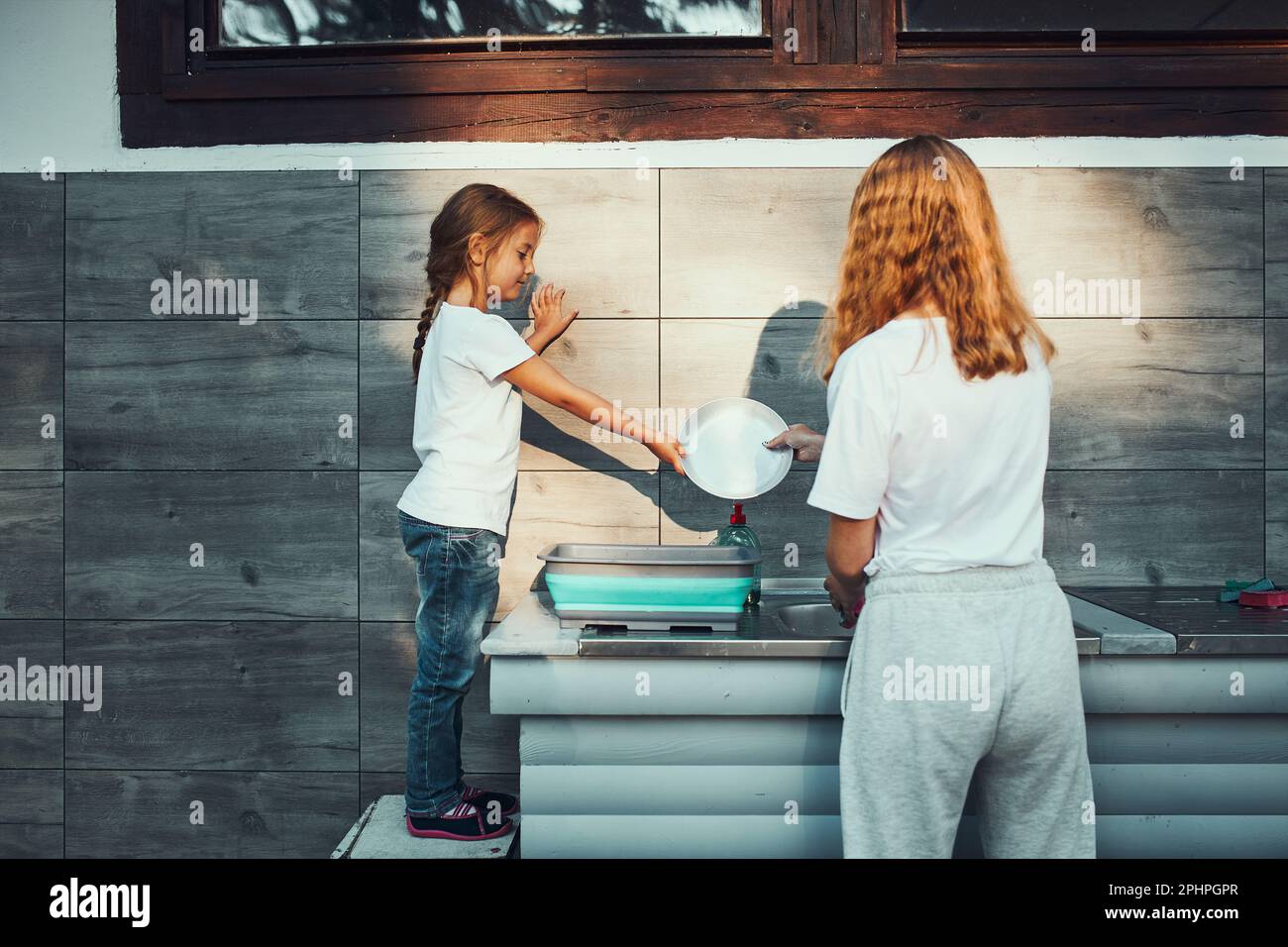 Teenager girl washing up the dishes pots and plates with help her ...