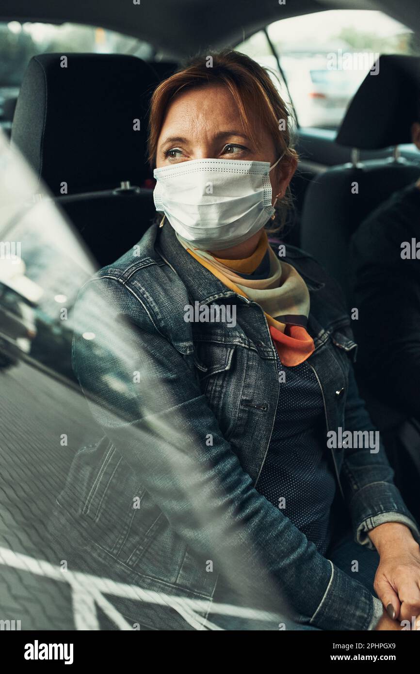 Woman sitting in a car wearing the face mask to avoid virus infection ...