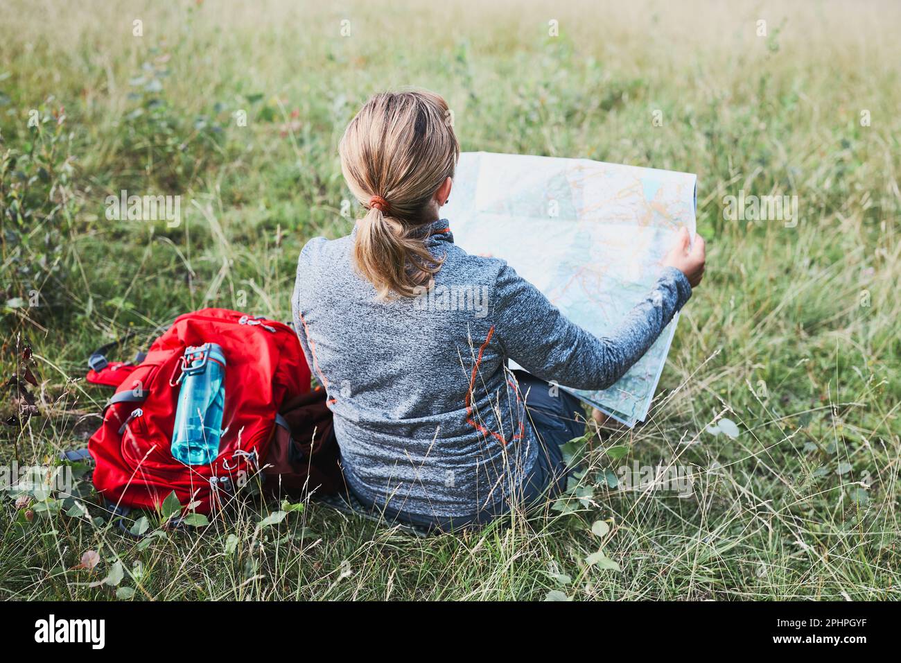 Woman with backpack having break during trip in mountains looking at ...