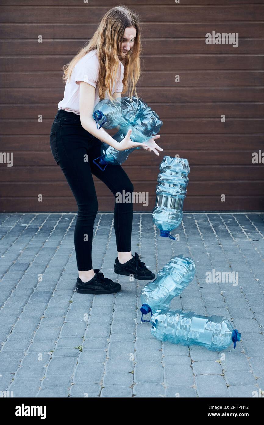 Young woman throwing out empty used plastic water bottles into trash ...