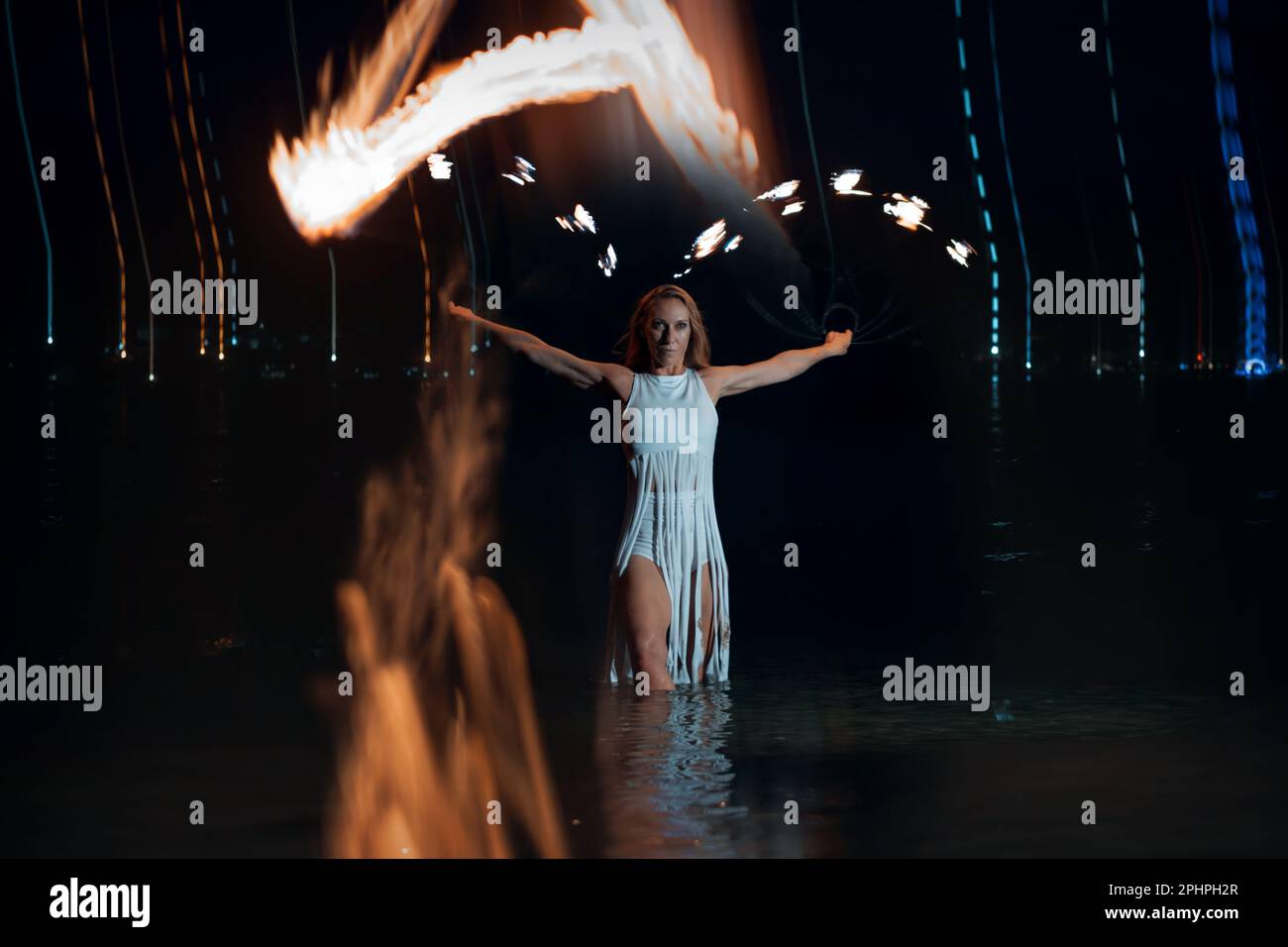 Caucasian woman dancing with fire in the water. Fire show at sea ...